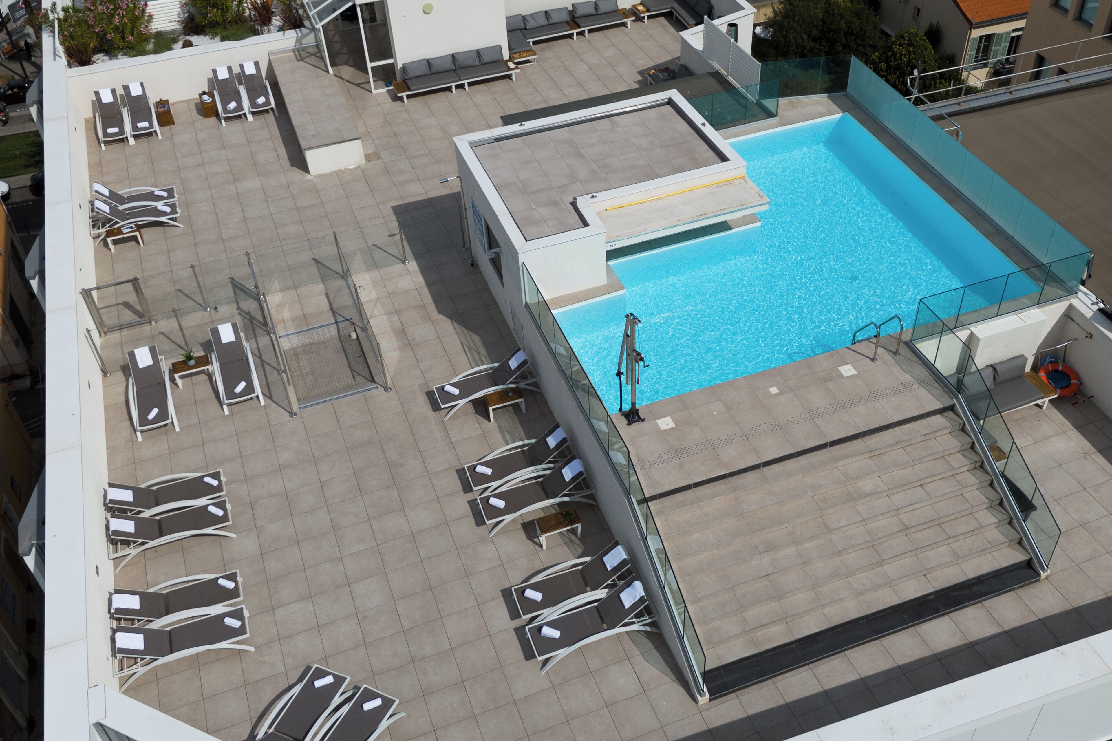 Área de piscina no terraço, com várias espreguiçadeiras e uma piscina.