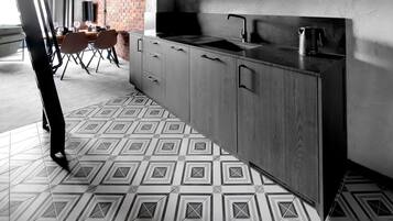 Cozinha moderna com piso de azulejos geométricos, pia embutida e área de refeições com cadeiras e mesa.