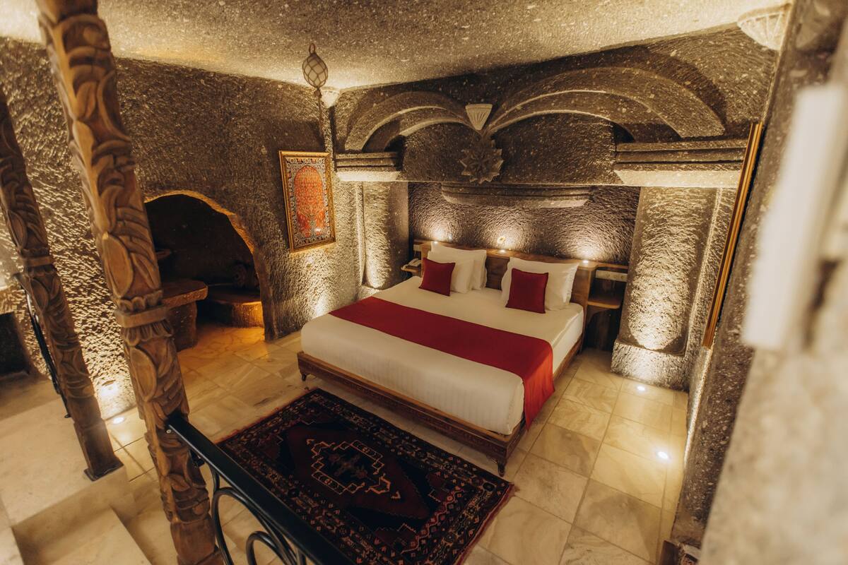 Quarto com uma cama grande, paredes de pedra e lareira.