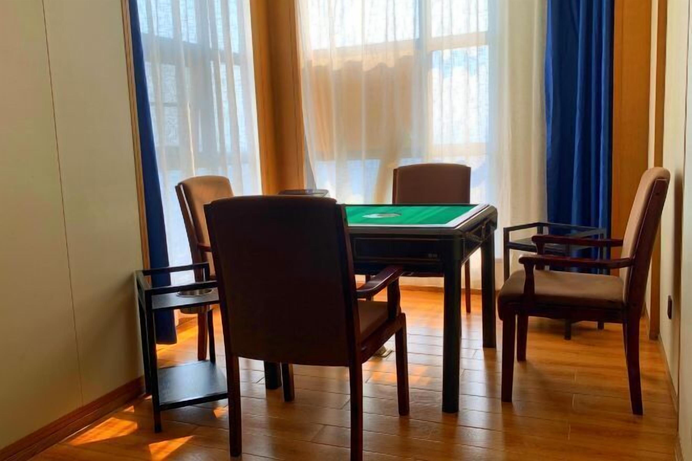 Quarto com mesa de bilhar, quatro cadeiras e janela com cortinas.