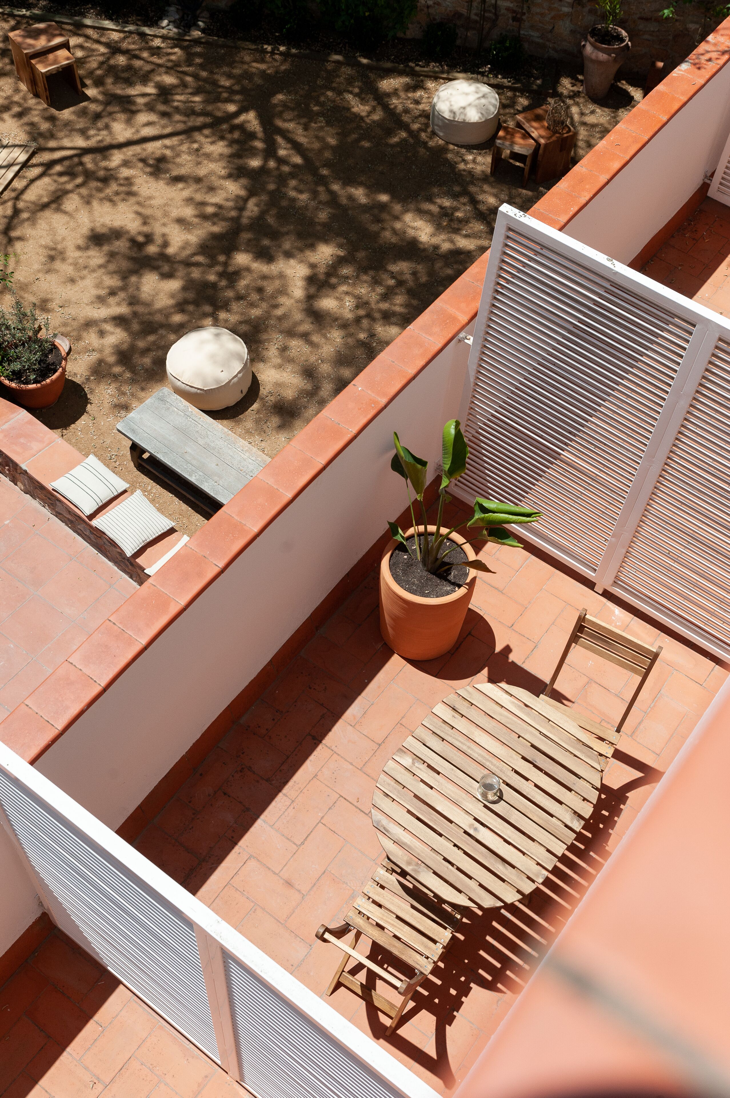 Terraço no telhado com mesa e cadeiras de madeira, plantas em vasos e um espaço de estar.