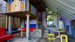 Estrutura de madeira em vários níveis, com área de jantar, sofá vermelho e banquetas amarelas.