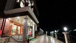 Entrada de um hotel com escadaria, parede xadrez e uma placa.