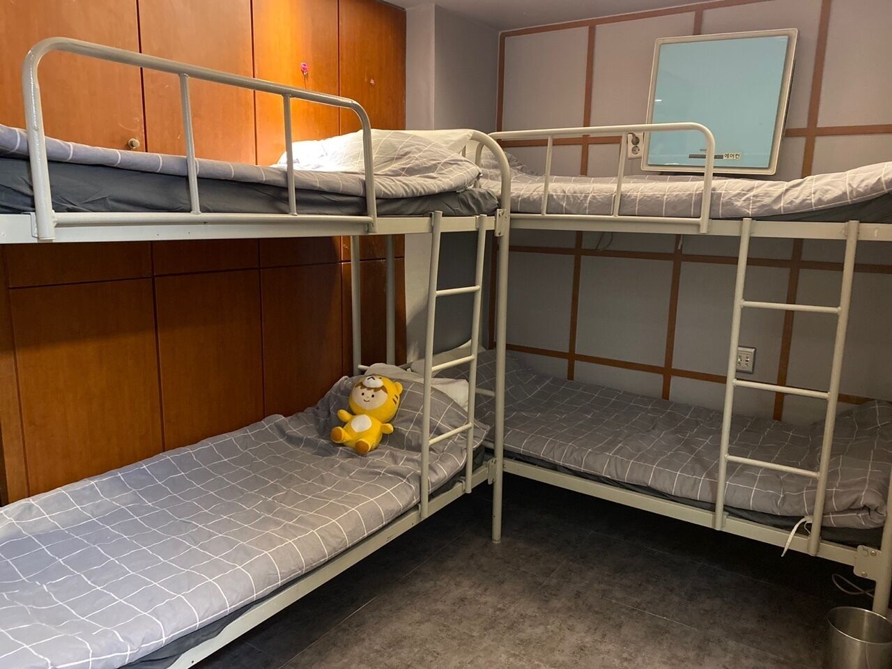 Quarto com beliche, guarda-roupa de madeira e uma pequena televisão na parede.