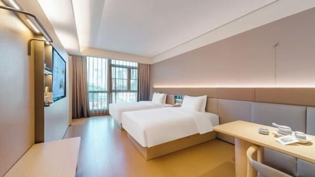 Quarto de hotel com uma cama grande, uma escrivaninha e vista para a cidade.