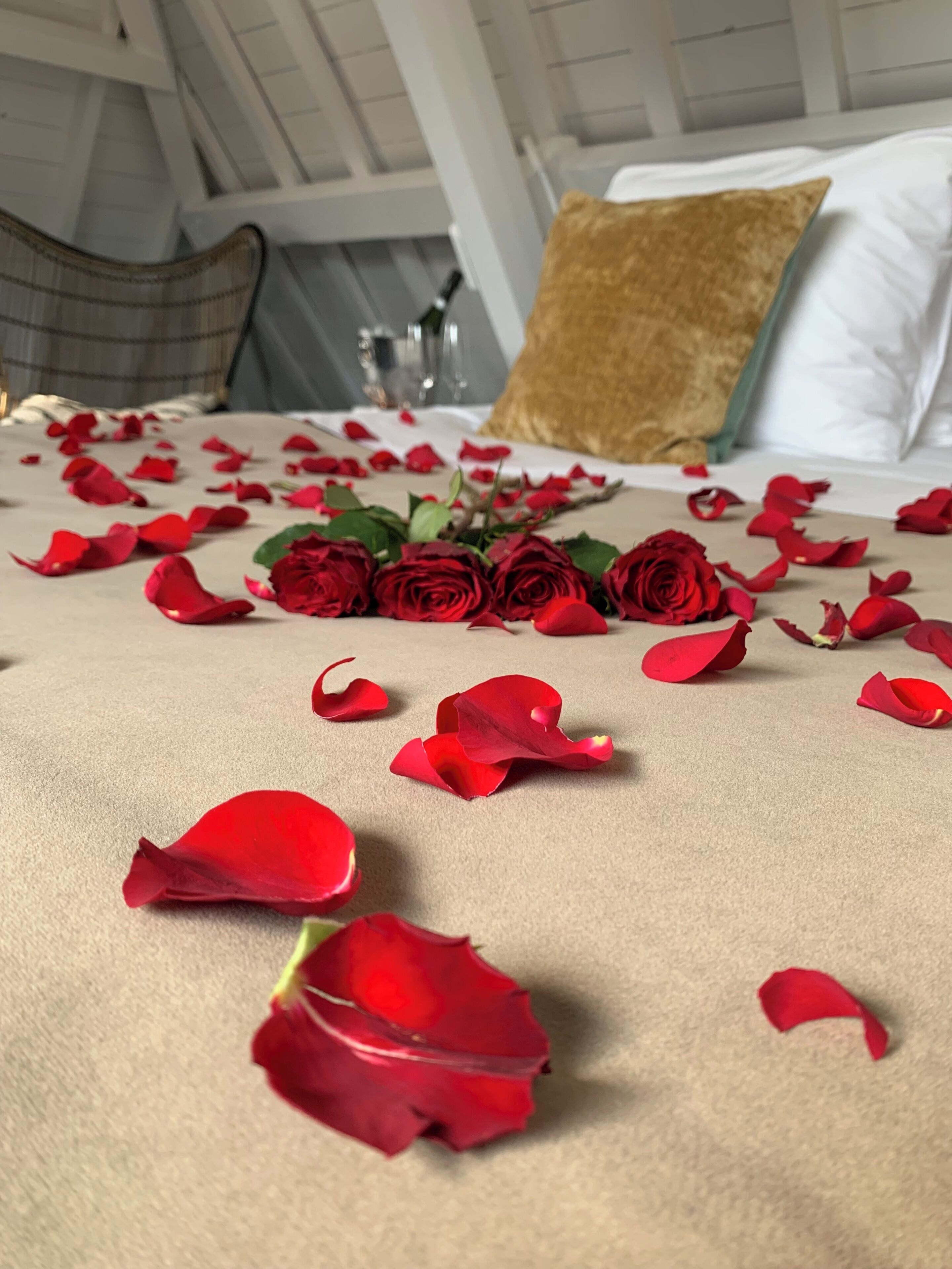 Uma cama com pétalas de rosa e rosas, um travesseiro marrom e um travesseiro branco.