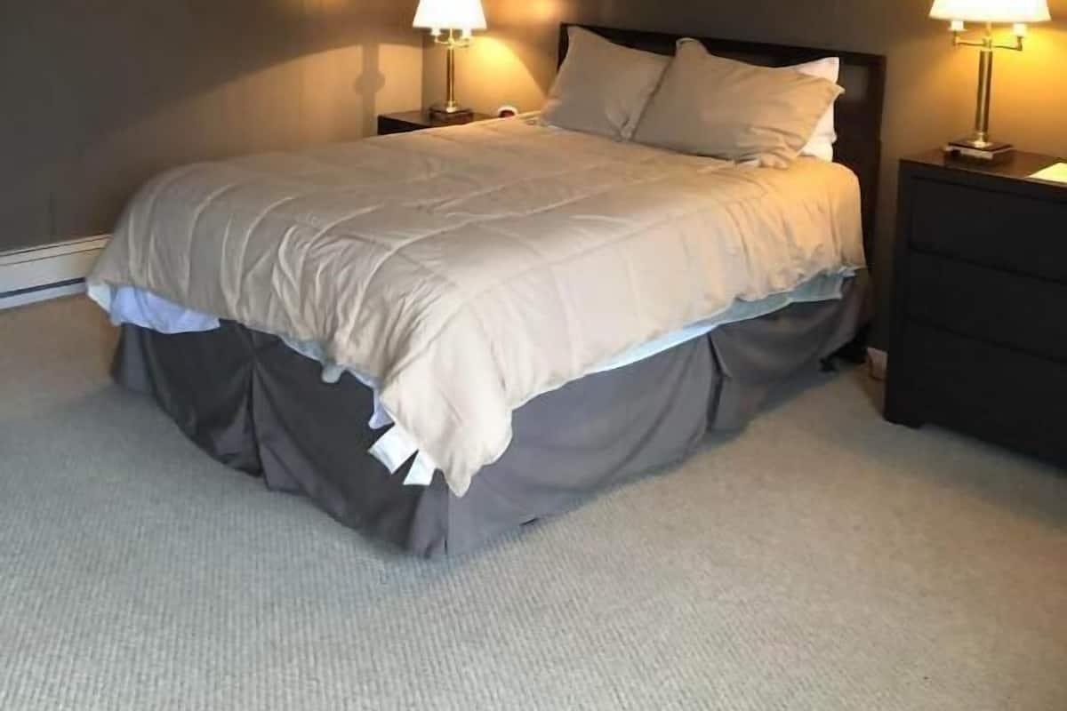 Quarto com uma cama, duas mesas de cabeceira e duas luminárias.