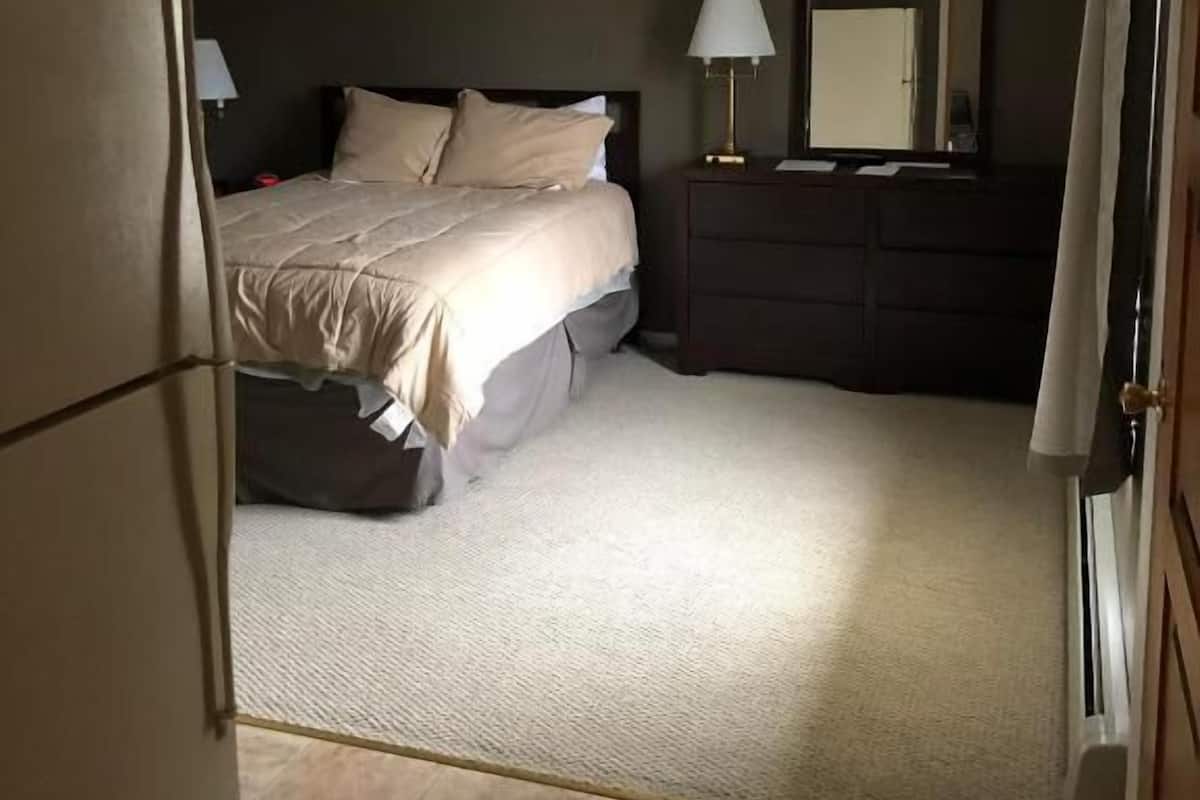 Quarto com cama, cômoda e geladeira.
