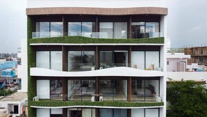 Um edifício moderno de vários andares com grandes janelas e varandas cobertas de plantas verdes.