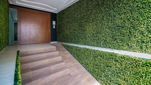 Um corredor com porta de madeira, parede verde e chão de azulejos.
