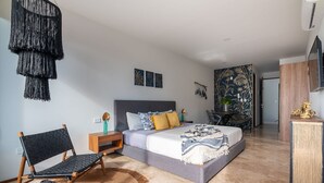 Quarto com cama, cadeira, mesa de cabeceira, um ornamento na parede e planta decorativa.