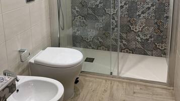 Uma casa de banho com sanita, bidé e cabine de duche.