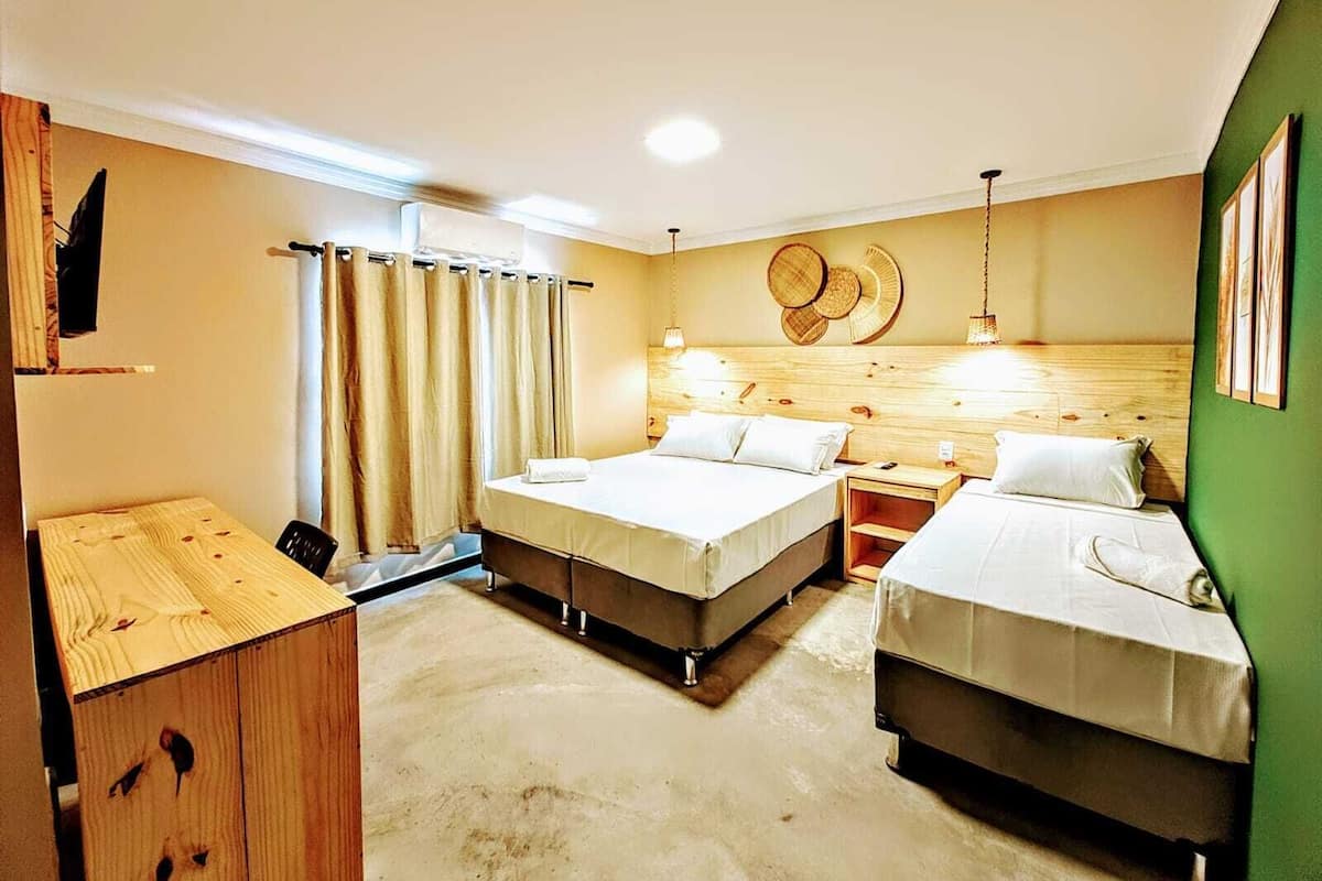 Quarto com duas camas, uma escrivaninha de madeira e um painel decorativo circular.
