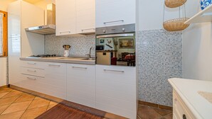 Uma cozinha moderna com armários brancos, forno embutido e painel de azulejos.