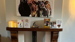 Um quarto acolhedor com lareira a lenha, uma mesa de exposição de bolos e uma mesa de centro com canecas.