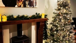Uma lareira com forno a lenha, uma árvore de Natal e um quadro na parede.