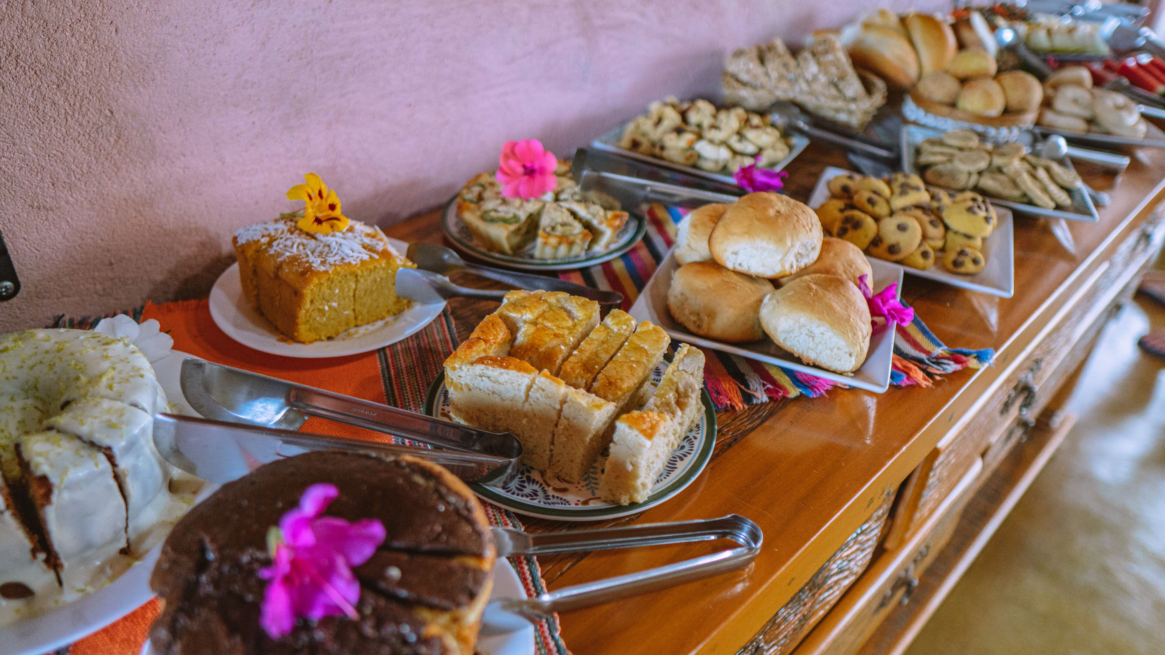 Buffet com diversas opções de comida, incluindo bolos, doces e biscoitos.