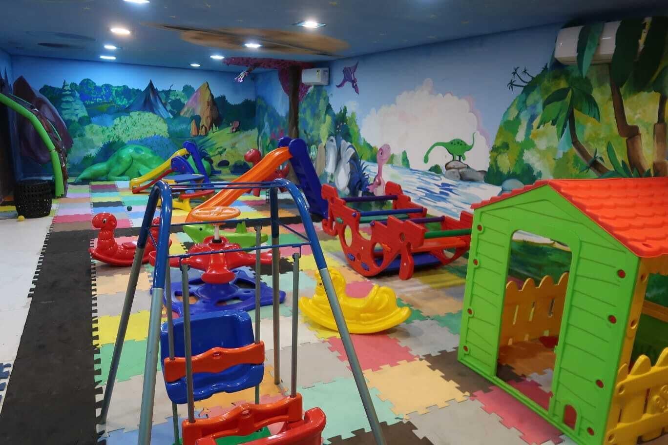 Uma área de recreação infantil com estruturas coloridas e uma casinha verde.
