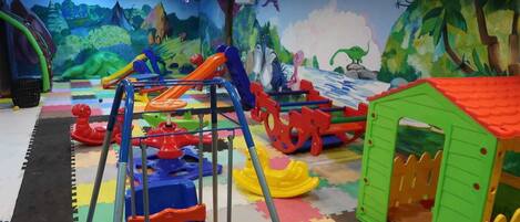 Uma área de recreação infantil com estruturas coloridas e uma casinha verde.