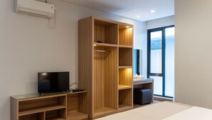Quarto moderno com cama, televisão, guarda-roupa de madeira e escrivaninha.