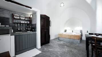 Uma cozinha moderna com armários cinzas, forno embutido e área de refeições com mesa e cadeiras de madeira.