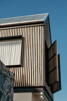 Um edifício moderno com telhado inclinado, revestimento de madeira e uma grande janela.