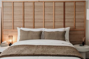 Uma cama com cabeceira, travesseiros e cobertor.