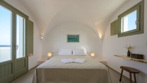 Um quarto com uma cama grande, duas luminárias de cabeceira, um quadro na parede e uma prateleira de madeira com um vaso.