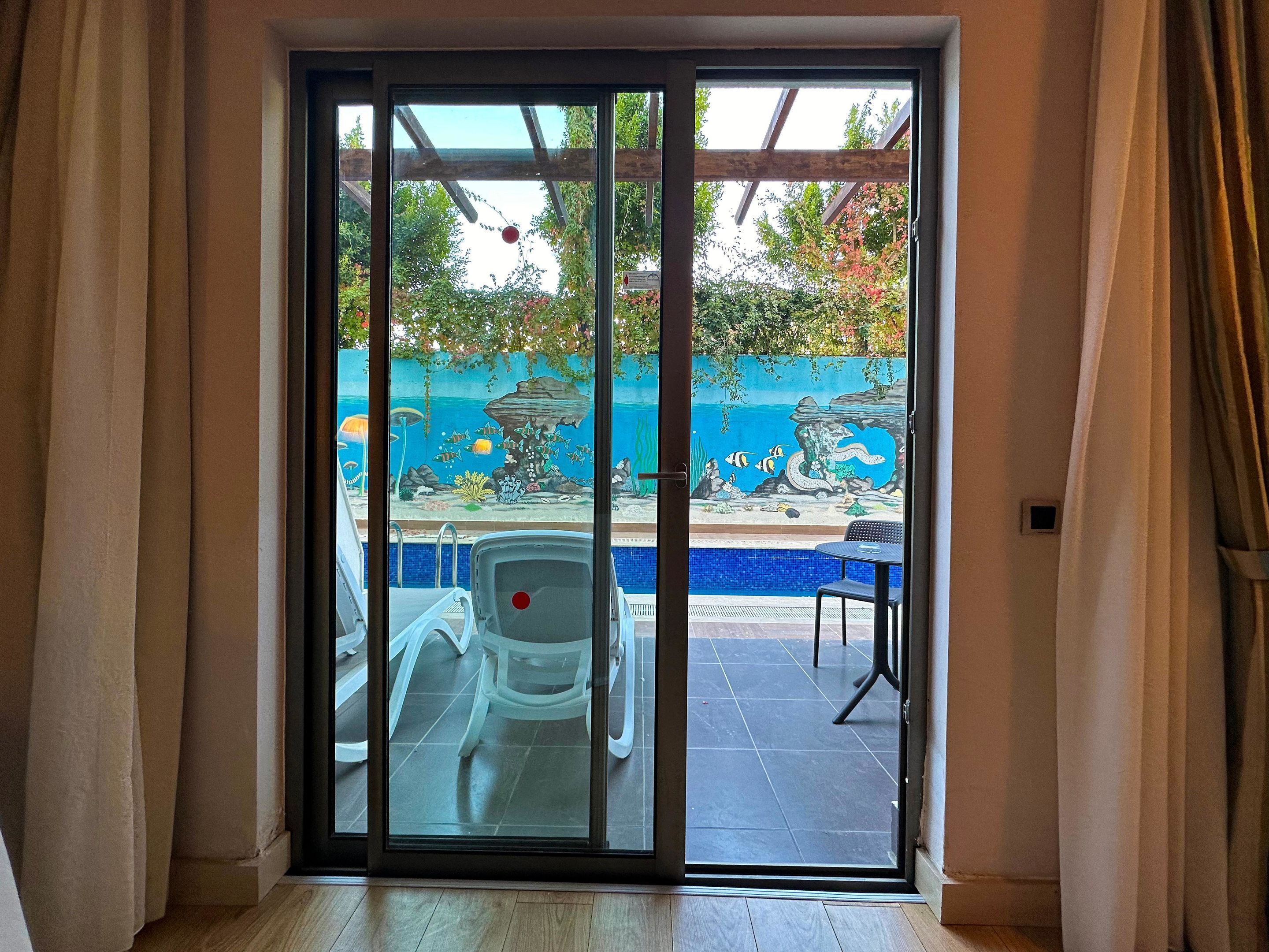 Quarto com porta de correr de vidro que dá para área externa com piscina e um mural.