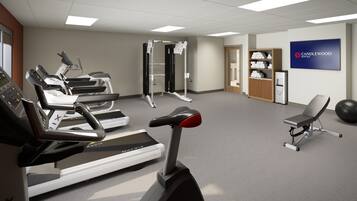 Sala de ginástica com esteiras, bicicleta ergométrica, aparelho de musculação e uma cadeira.