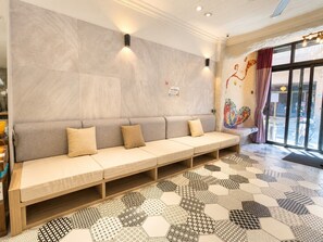 Um hall de hotel moderno com um banco comprido, piso estampado e um mural na parede.