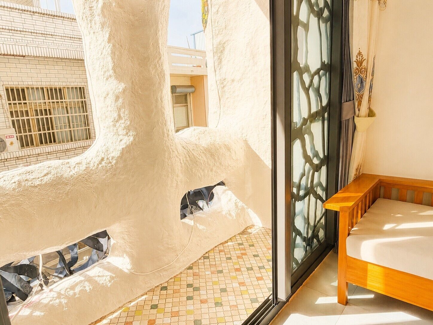Um quarto com uma janela grande, um banco e piso de azulejos.