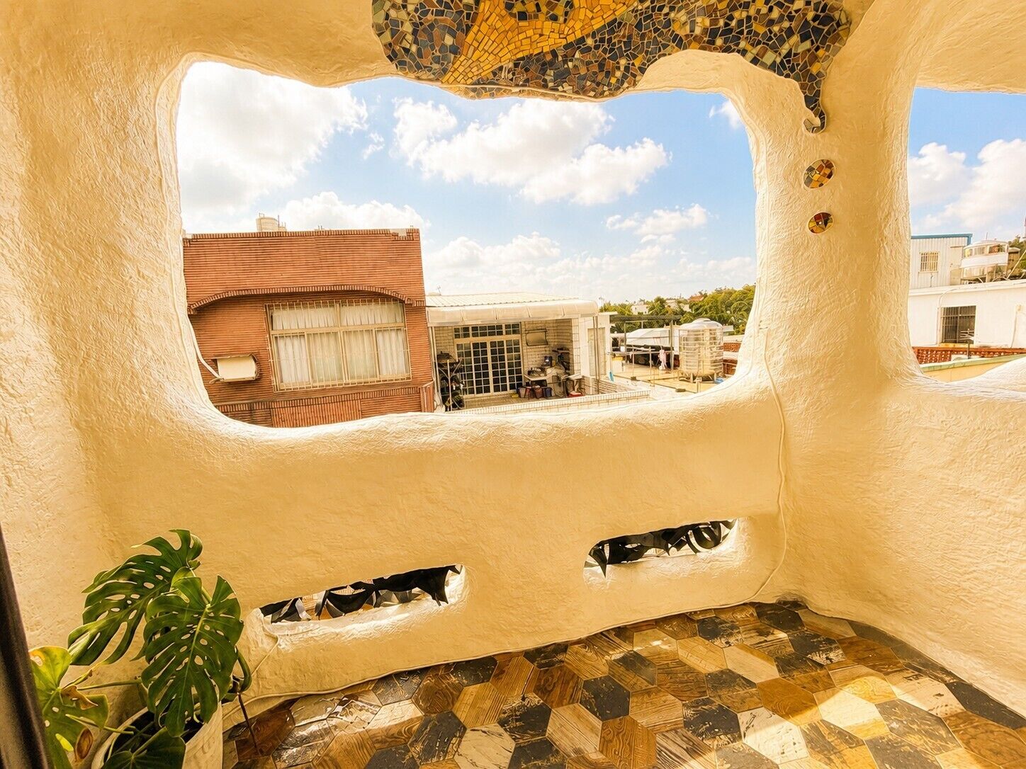 Um quarto com teto curvo único, vista para edifícios externos e uma planta em vaso.