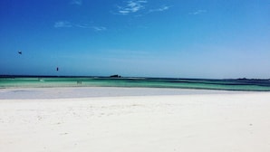 Uma praia com águas turquesa translúcidas e uma faixa de areia.