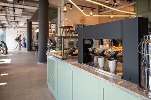 Um café com design moderno, incluindo uma máquina de café, xícaras e uma vitrine de vidro.