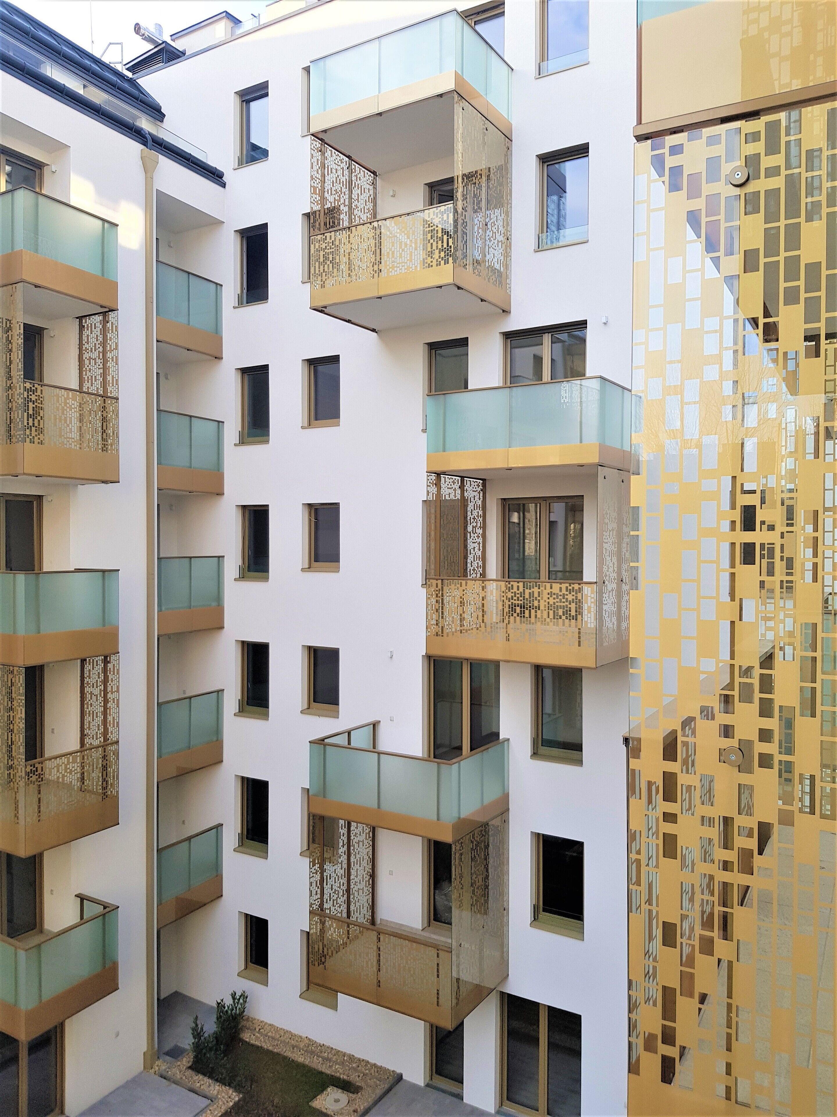 Um edifício residencial com vários andares, varandas, janelas grandes e um telhado plano.