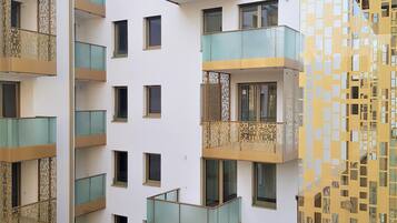 Um edifício residencial com vários andares, varandas, janelas grandes e um telhado plano.