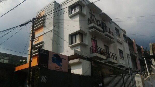 Edifício com várias andares, varandas e um letreiro indicando espaço comercial ou escritório.