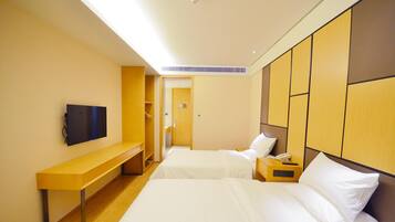 Quarto de hotel com duas camas, televisão, escrivaninha e guarda-roupa.