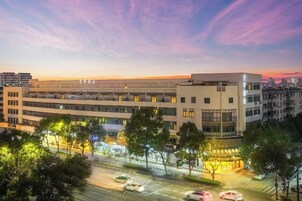 Um edifício com vários andares e garagem subterrânea, rodeado por árvores e postes de luz.