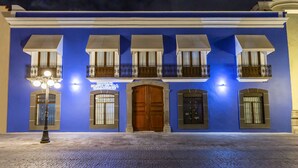 Fachada de hotel com exterior azul, várias varandas e uma entrada imponente.