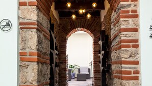 Um corredor de tijolos em arco com um candeeiro no teto e uma porta no final.