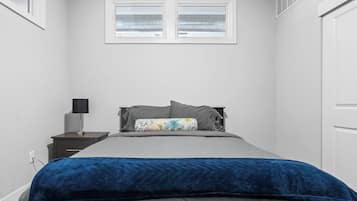 Um quarto com uma cama, uma mesinha de cabeceira, uma luminária e uma janela.