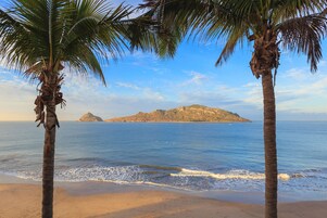 Uma praia com palmeiras e uma ilha ao longe.