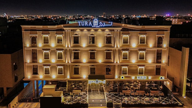 Um hotel com uma placa indicando "TURA HOTEL" e "MUD" no andar térreo.