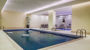 Piscina com água azul cristalina, rodeada por espreguiçadeiras e um vaso de planta.