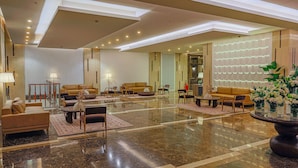 Um hall amplo com piso de mármore, sofás de couro e diversas opções de assento.