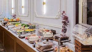 Um balcão de buffet com diversos alimentos, incluindo bolos, doces e frutas.