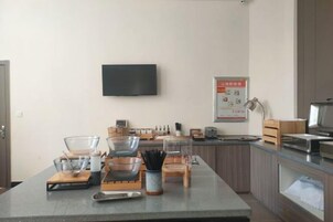 Cozinha com televisão de tela plana na parede, bancadas de madeira e diversos eletrodomésticos.