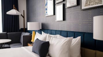 Quarto de hotel com cama, sofá, abajur e uma parede com quadros.